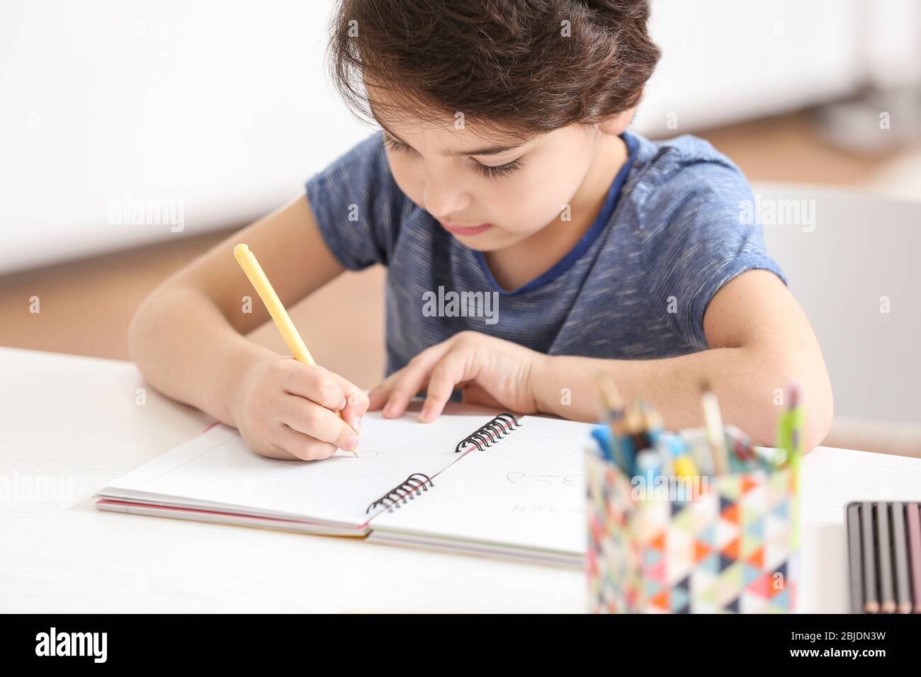 Cute little boy writing something in notebook Stock Photo - Alamy