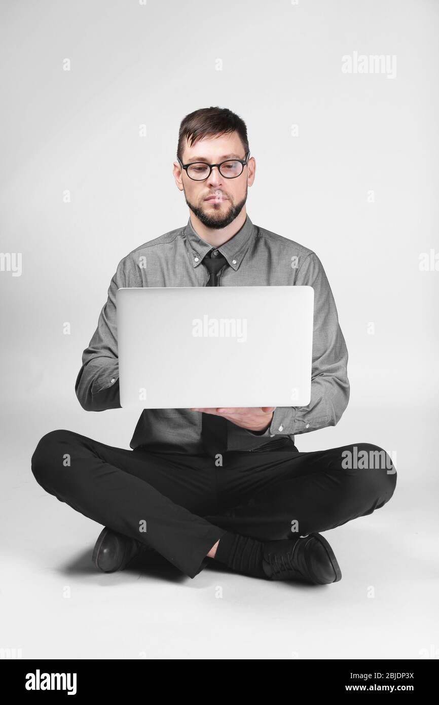 Handsome young programmer with laptop on light background Stock Photo ...