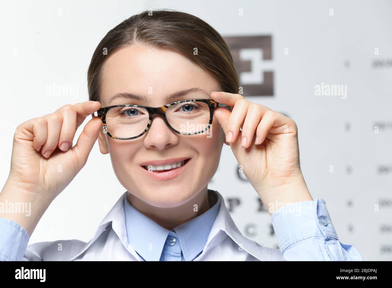 Young woman with spectacles on eyesight test chart background Stock ...