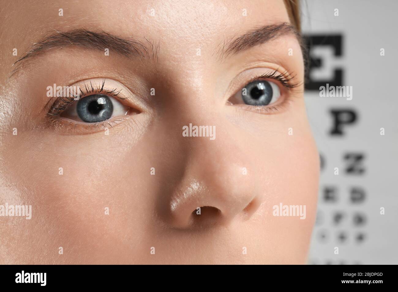Young woman on eyesight test chart background Stock Photo - Alamy