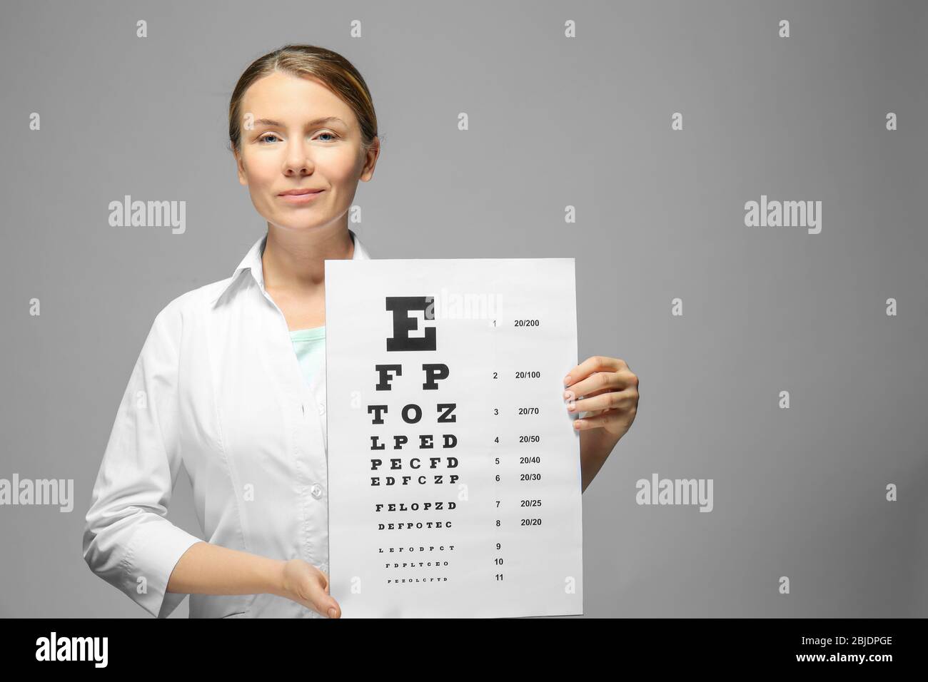 Young doctor holding eyesight test chart on grey background Stock Photo ...