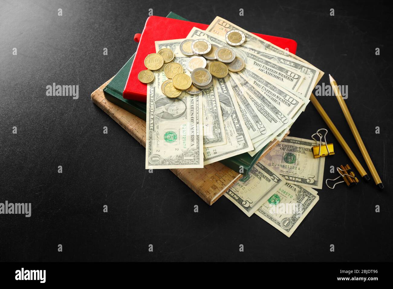 School supplies, dollar banknotes and coins on blackboard. Pocket money ...