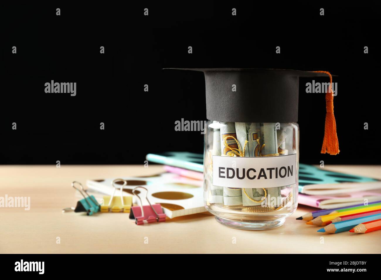 School supplies and glass jar with money for education on wooden table ...