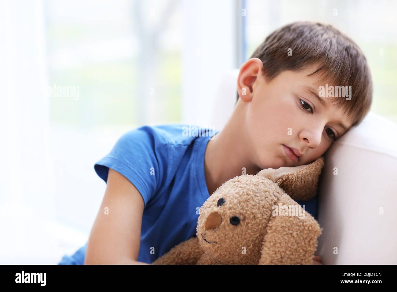 Sad little boy sitting on armchair, closeup Stock Photo - Alamy