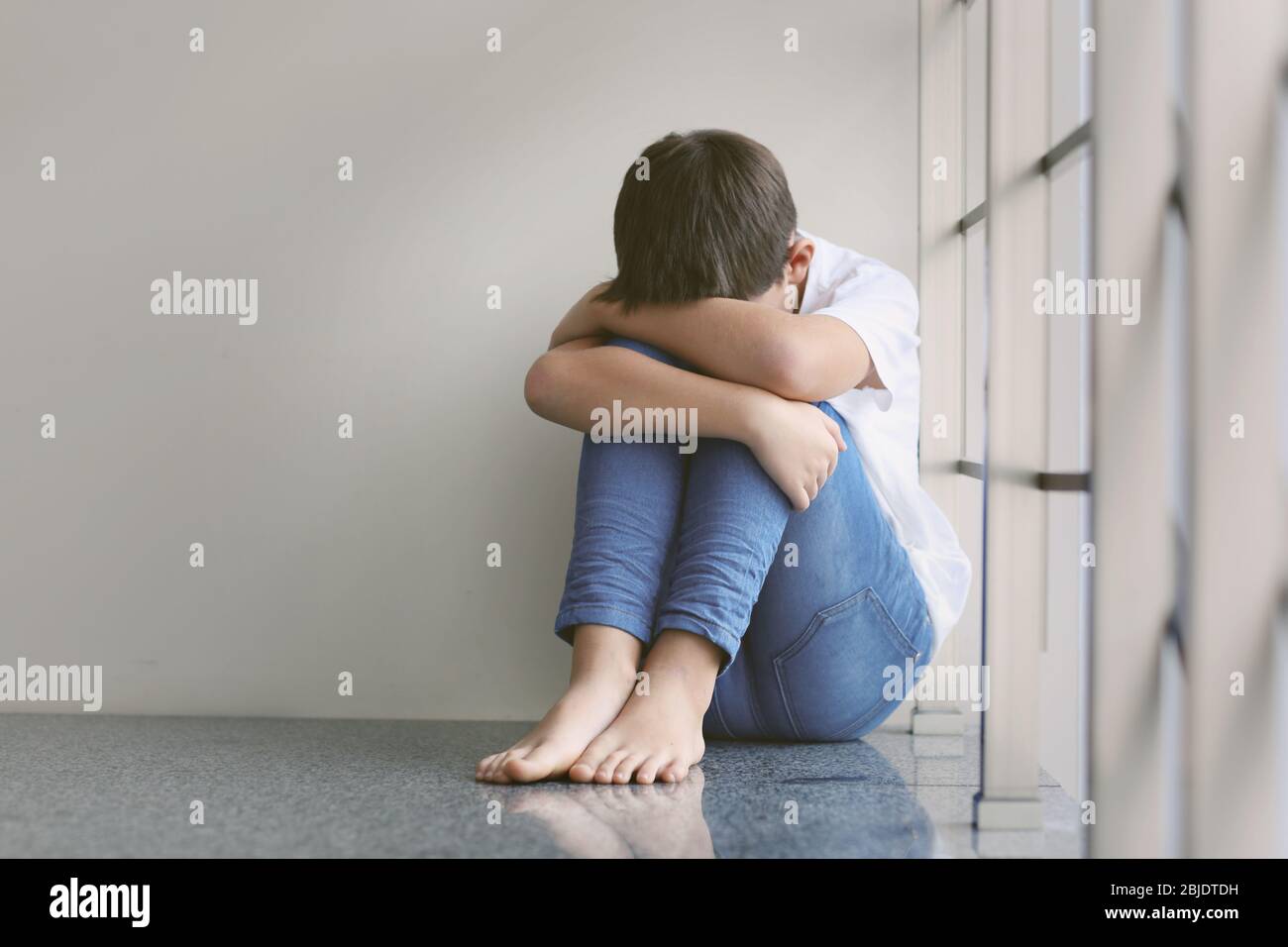 Sad little boy sitting beside wall Stock Photo - Alamy