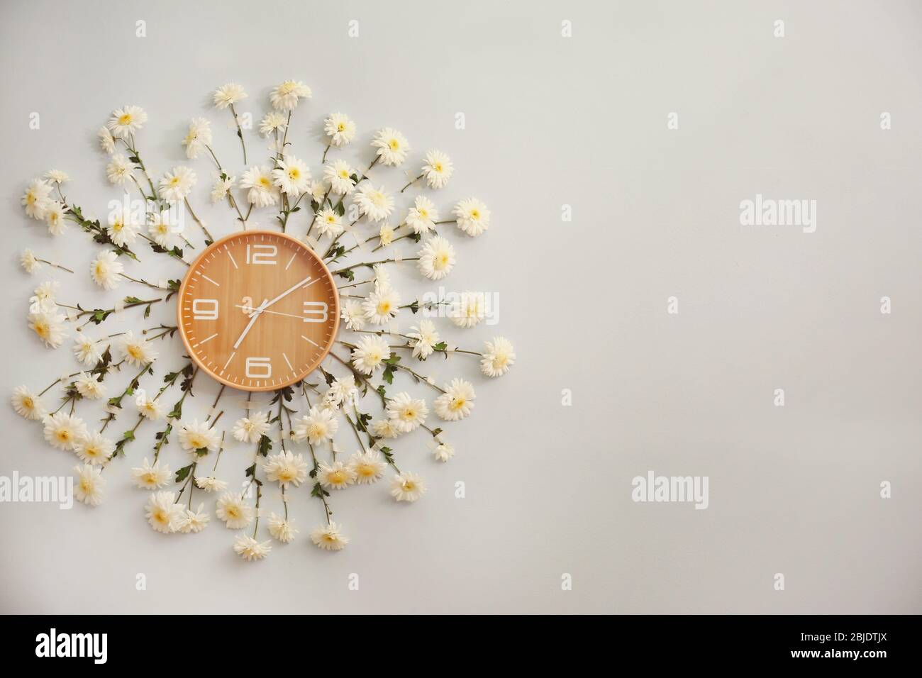Clock decorated with flowers on light wall Stock Photo - Alamy