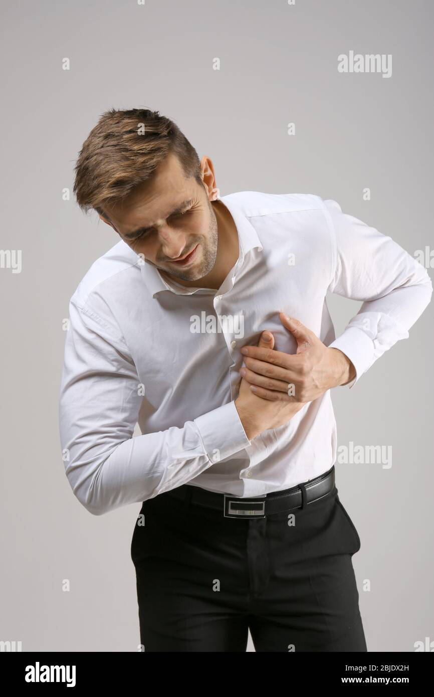 Young man suffering from pain on grey background Stock Photo - Alamy