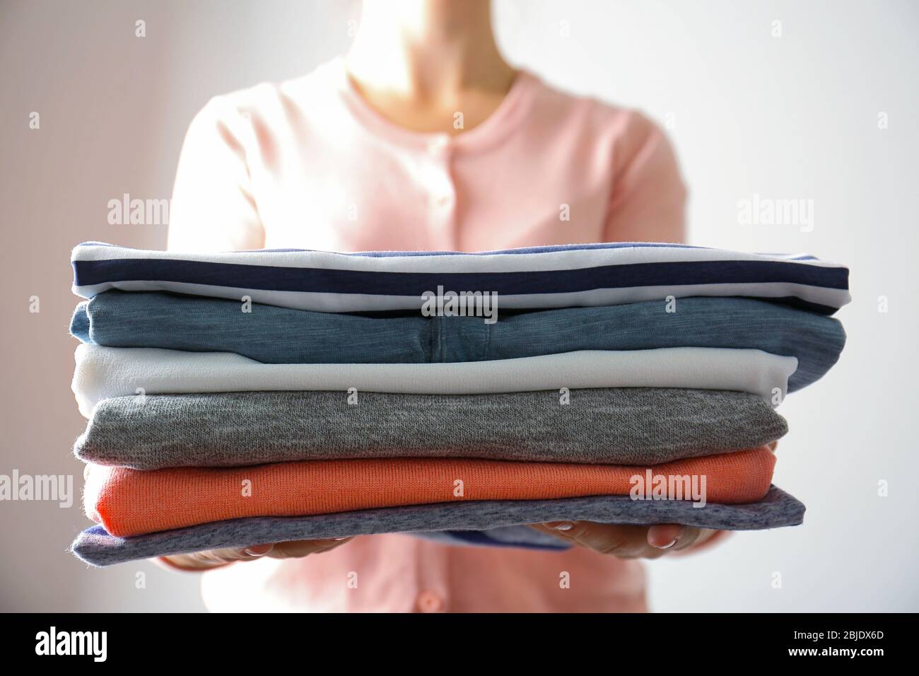 Woman holding folded clothes in hands, closeup Stock Photo - Alamy