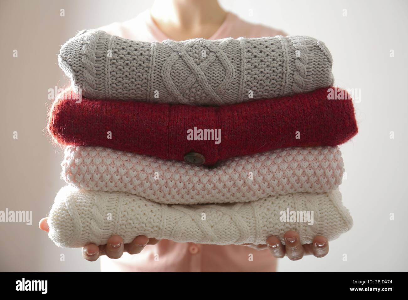 Woman holding folded clothes in hands, closeup Stock Photo - Alamy