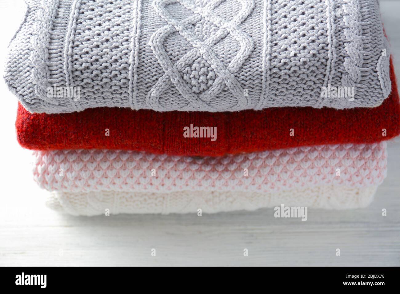 Stack of warm winter clothes on white wooden background Stock Photo - Alamy