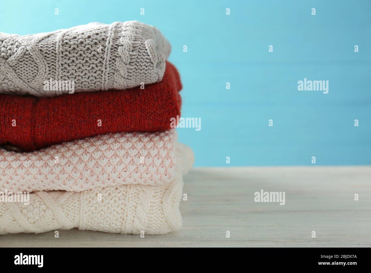 Stack of warm winter clothes on blue wooden background Stock Photo - Alamy