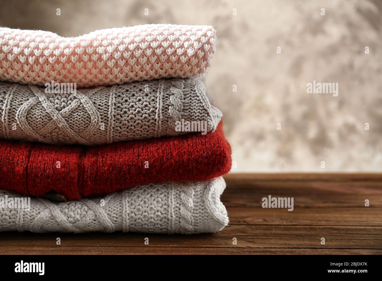 Stack of warm winter clothes on wooden table Stock Photo - Alamy