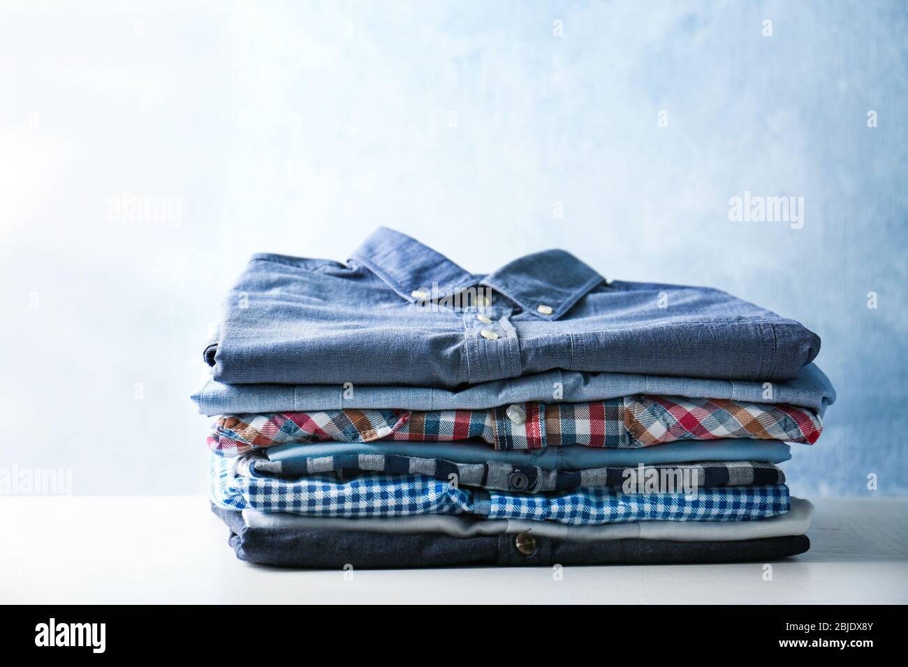 Stack of colorful clothes on blue background Stock Photo - Alamy