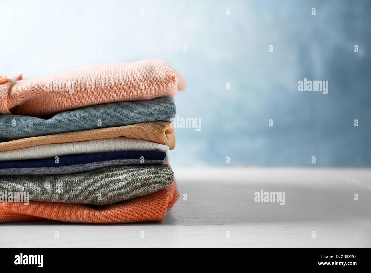Stack of colorful clothes on blue background Stock Photo - Alamy