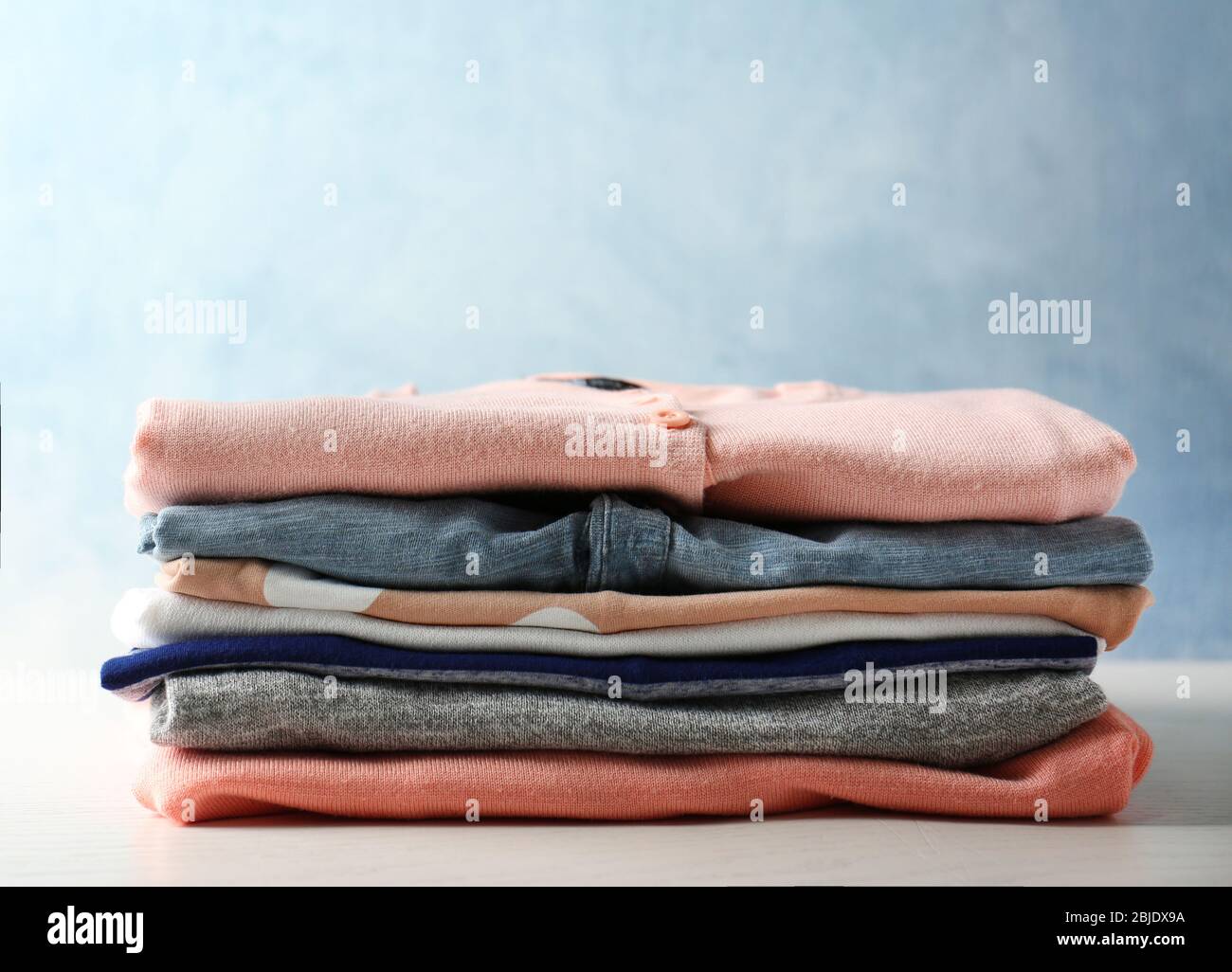 Stack of colorful clothes on light background Stock Photo - Alamy