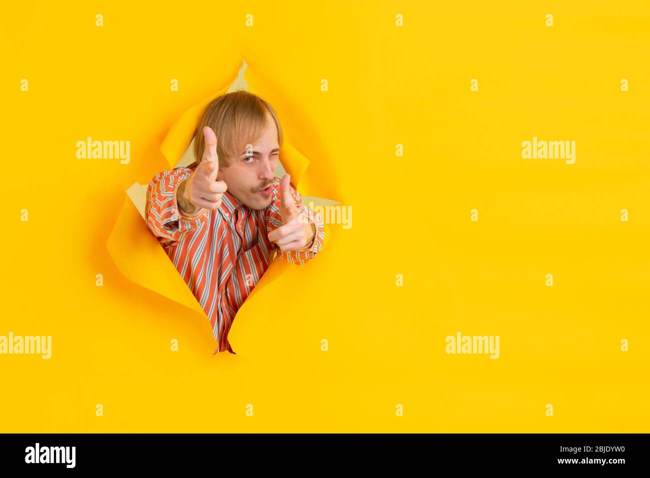 Pointing, choosing. Cheerful caucasian young man poses in torn yellow ...