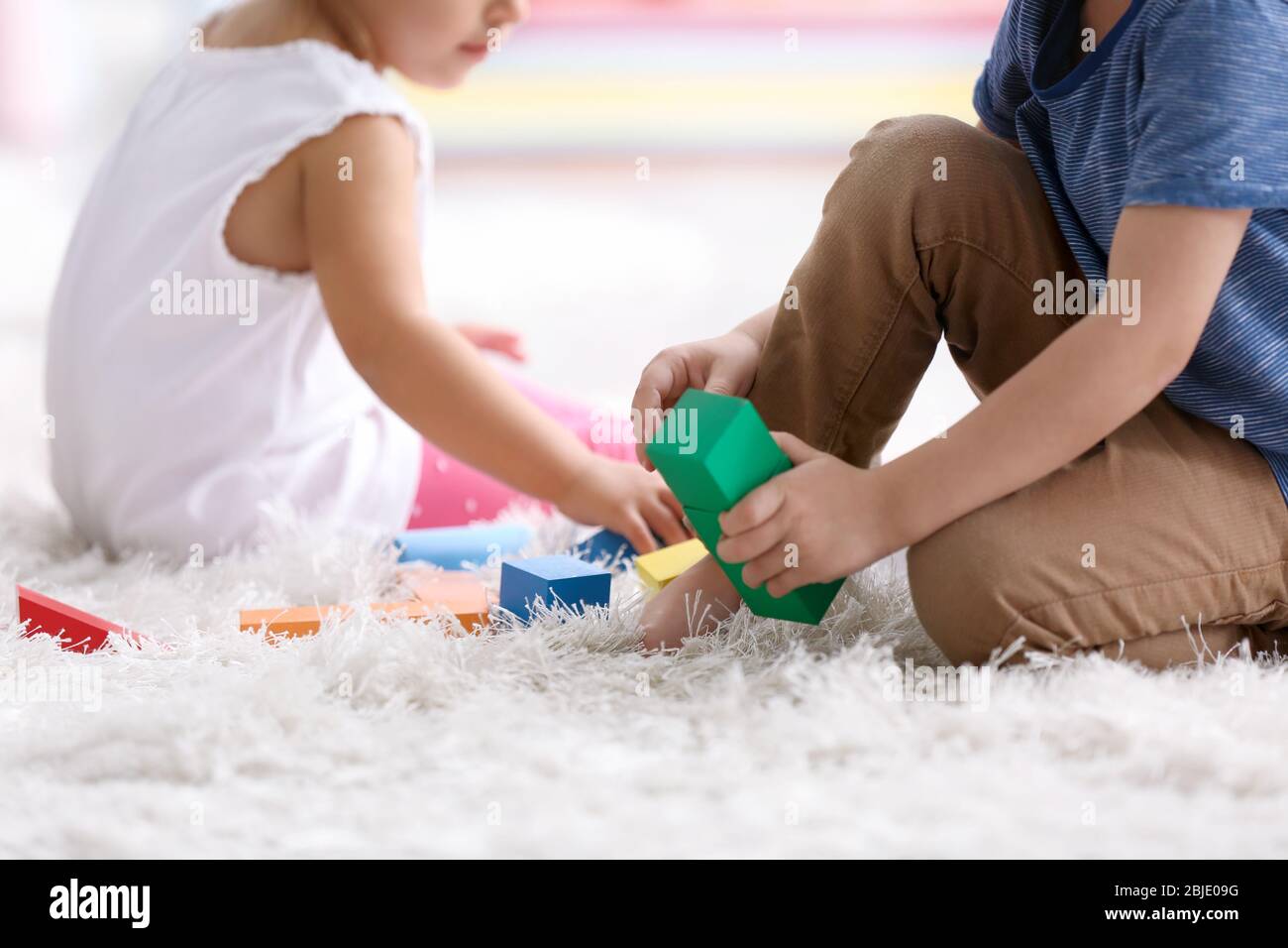 Cute little children playing while sitting on carpet at home Stock ...