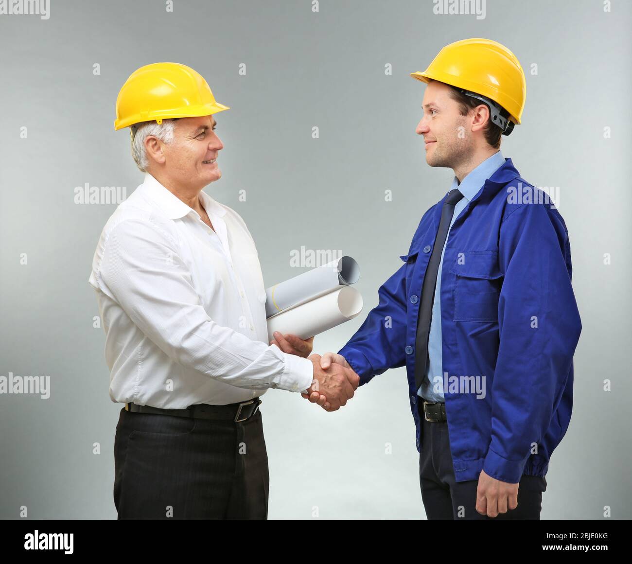 Senior engineer and worker shaking hands on light background Stock ...