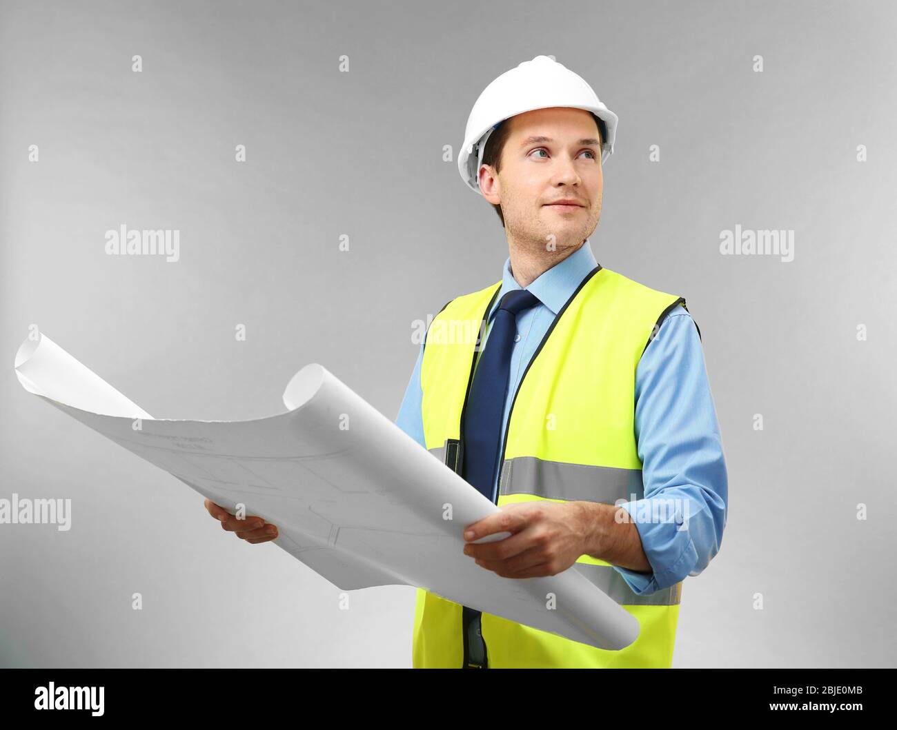 Handsome engineer with drawing on light background Stock Photo - Alamy