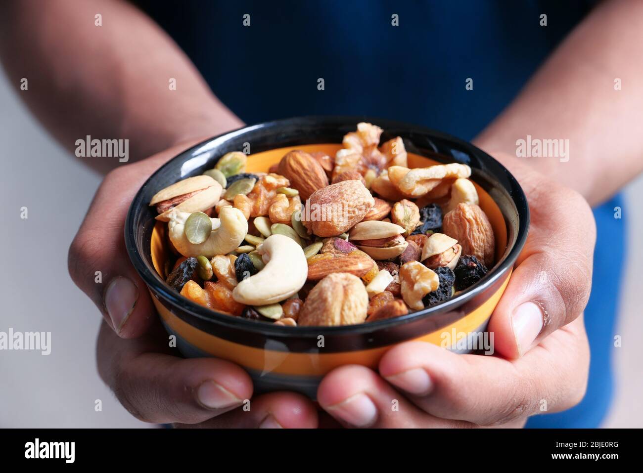 Man hand holding a bowl of Mixed nuts Stock Photo - Alamy