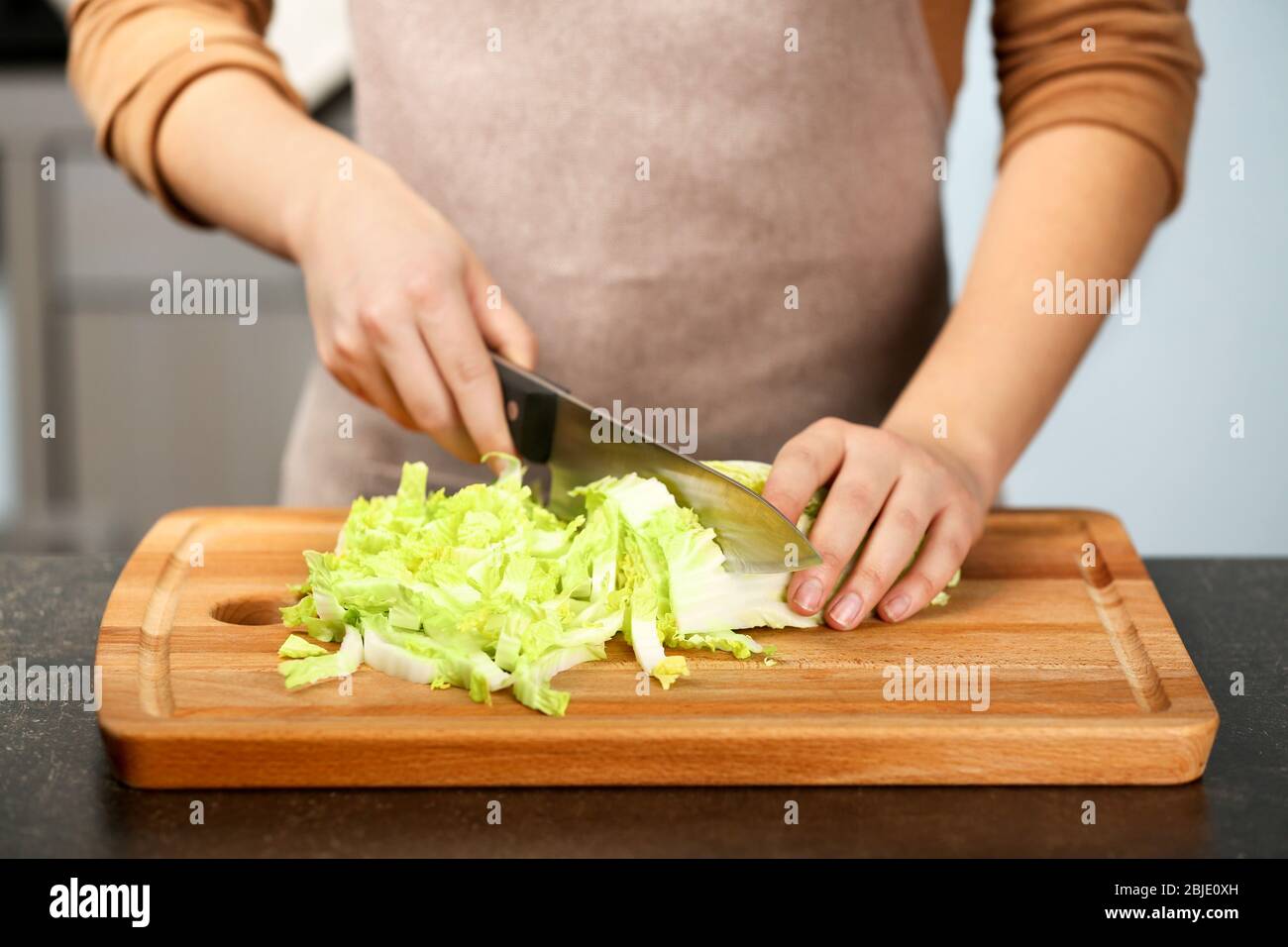 Female hands cutting Chinese cabbage at table in kitchen Stock Photo ...