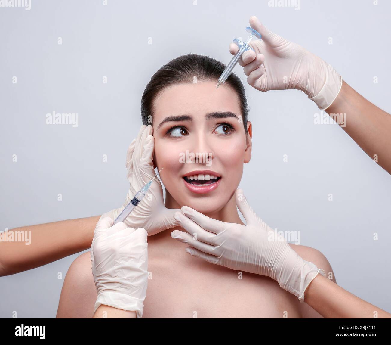 Beautiful young woman receiving filler injections in face, on light ...