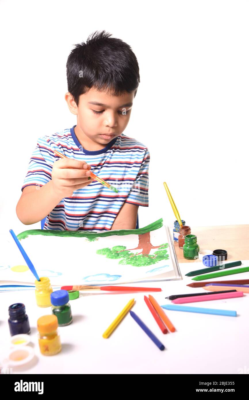 High Key image of Young Indian Boy drawing and painting on the paper in ...