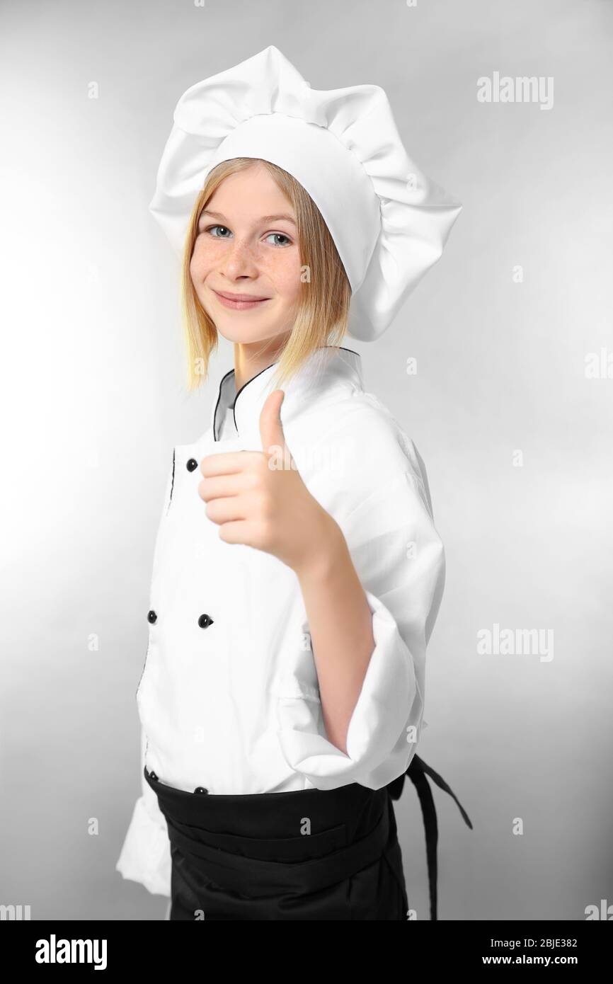 Cute girl in chef uniform on light background Stock Photo - Alamy