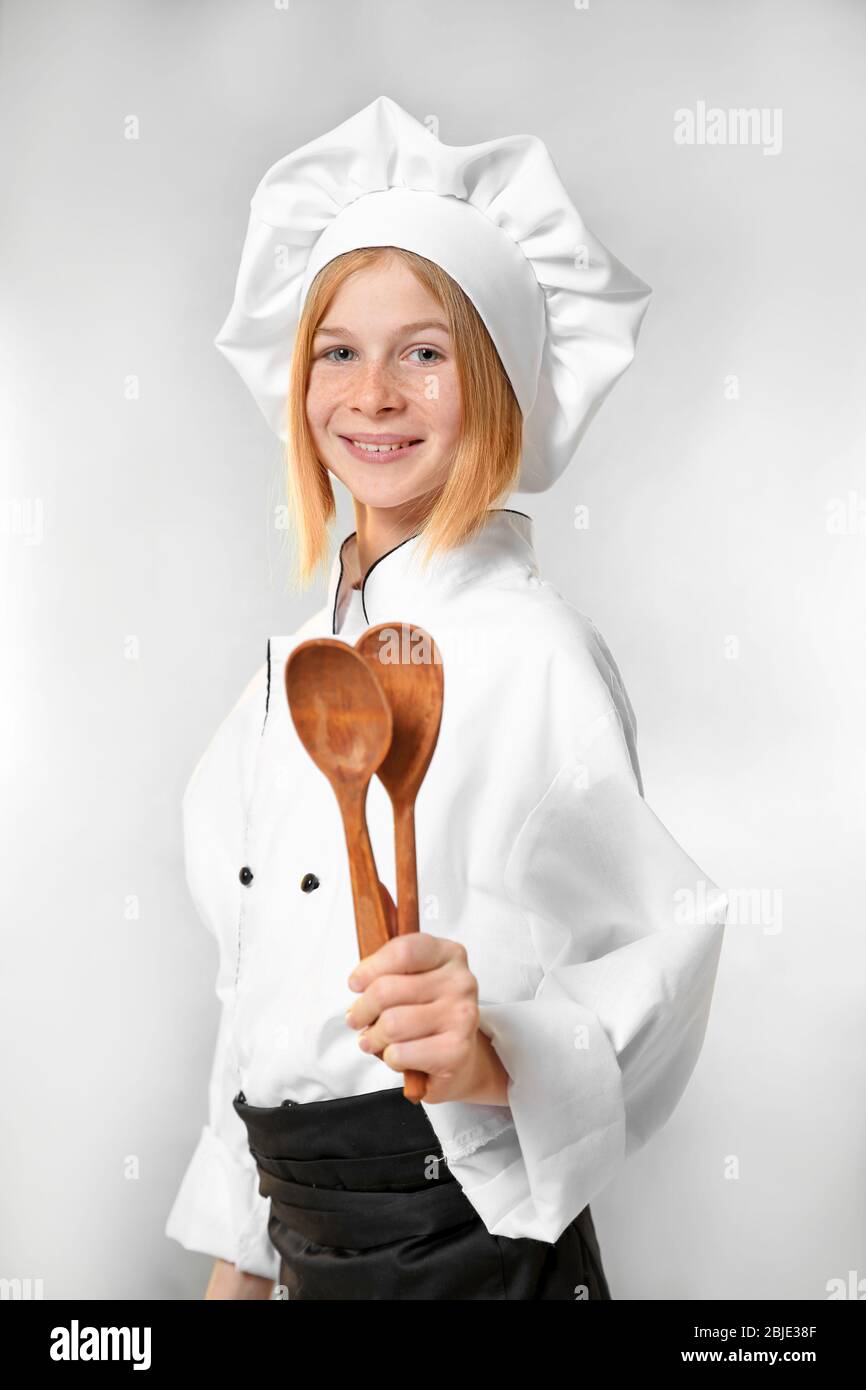 Cute girl in chef uniform on light background Stock Photo - Alamy
