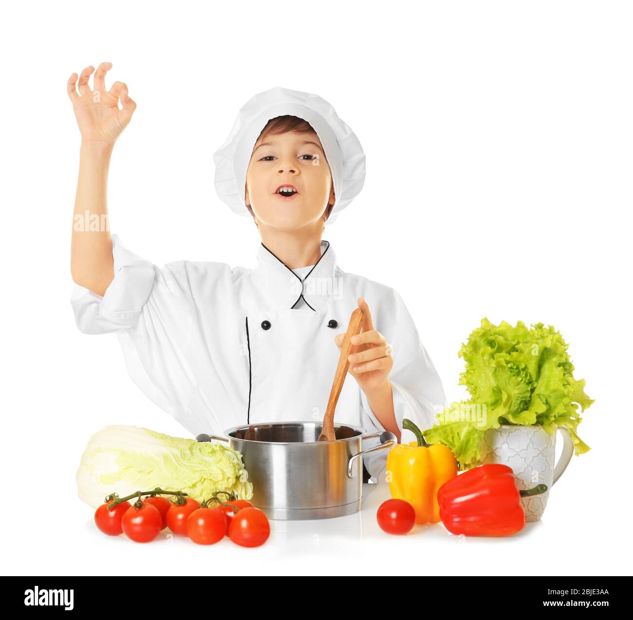 Cute boy in chef uniform preparing tasty soup, on white background ...
