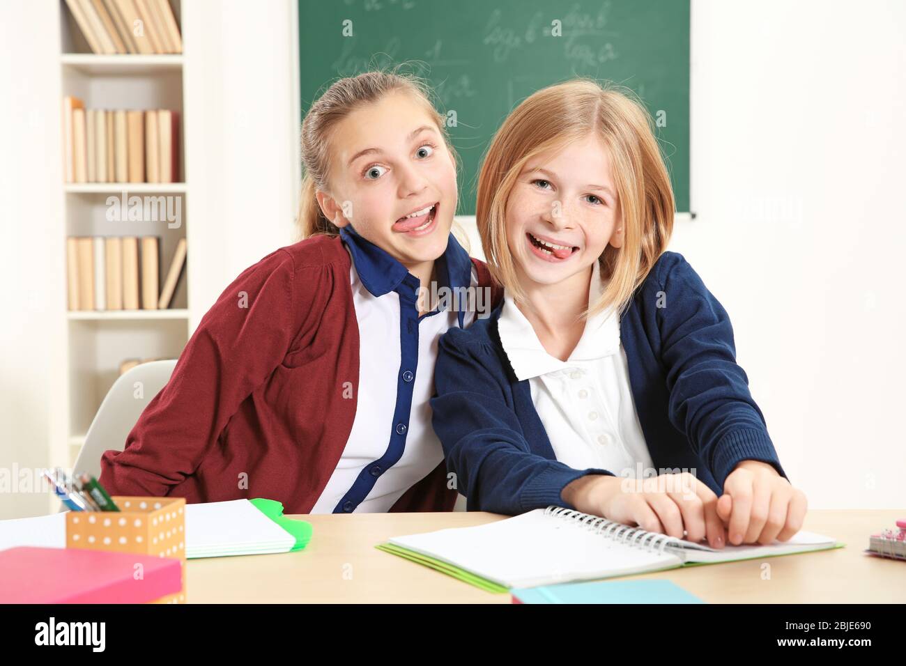 Two cute girls sitting at desk in school class Stock Photo - Alamy