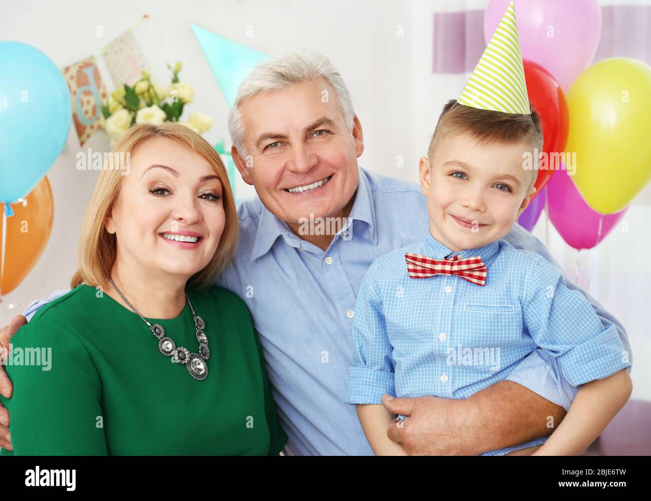 Grandparents with their grandchild at birthday party Stock Photo - Alamy