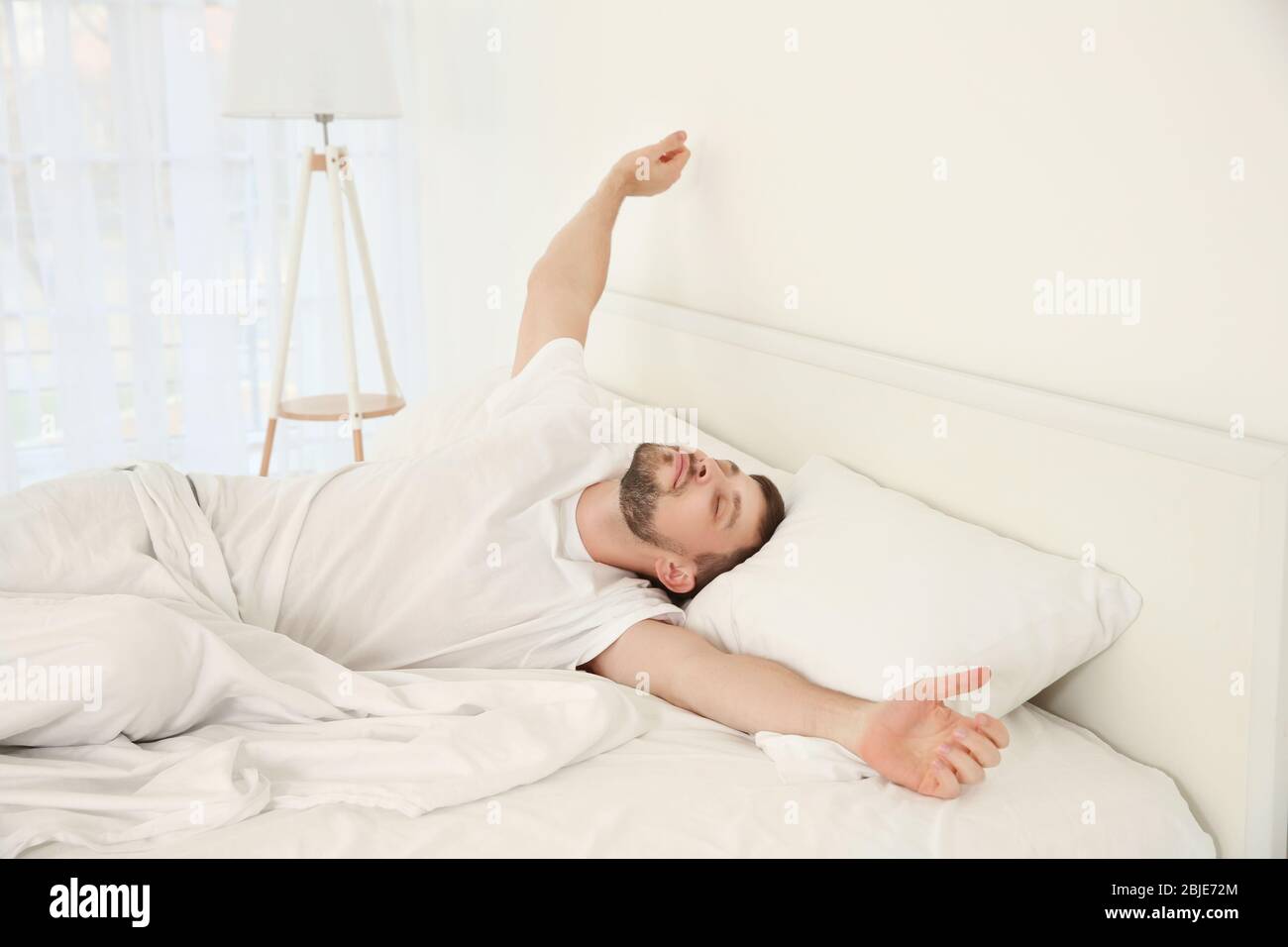 Young attractive man waking up in the morning Stock Photo - Alamy