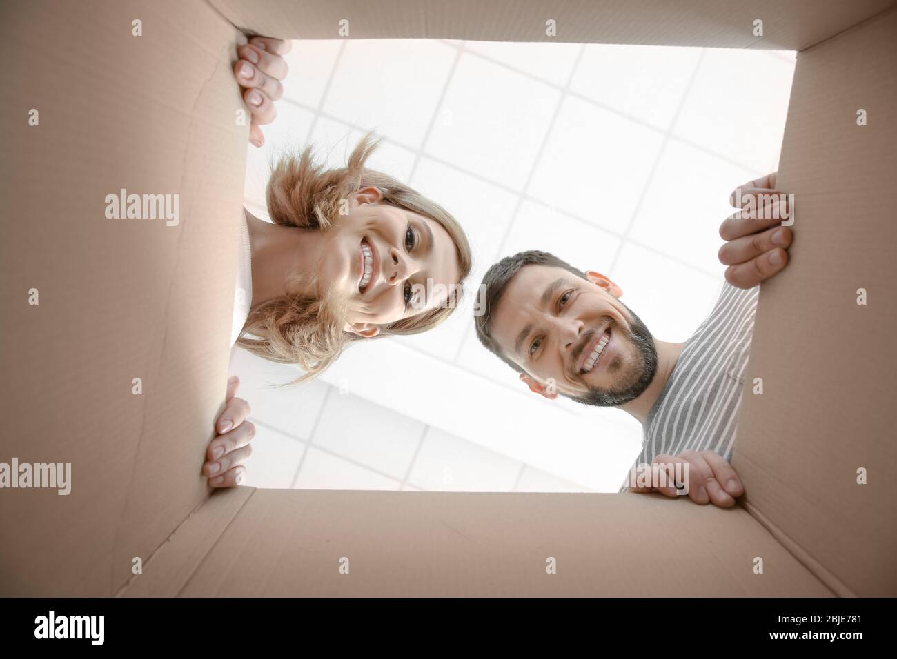 Young family couple looking through box. Moving concept Stock Photo - Alamy