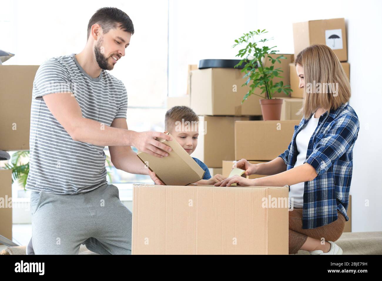 Happy family packing boxes in room. Moving concept Stock Photo - Alamy