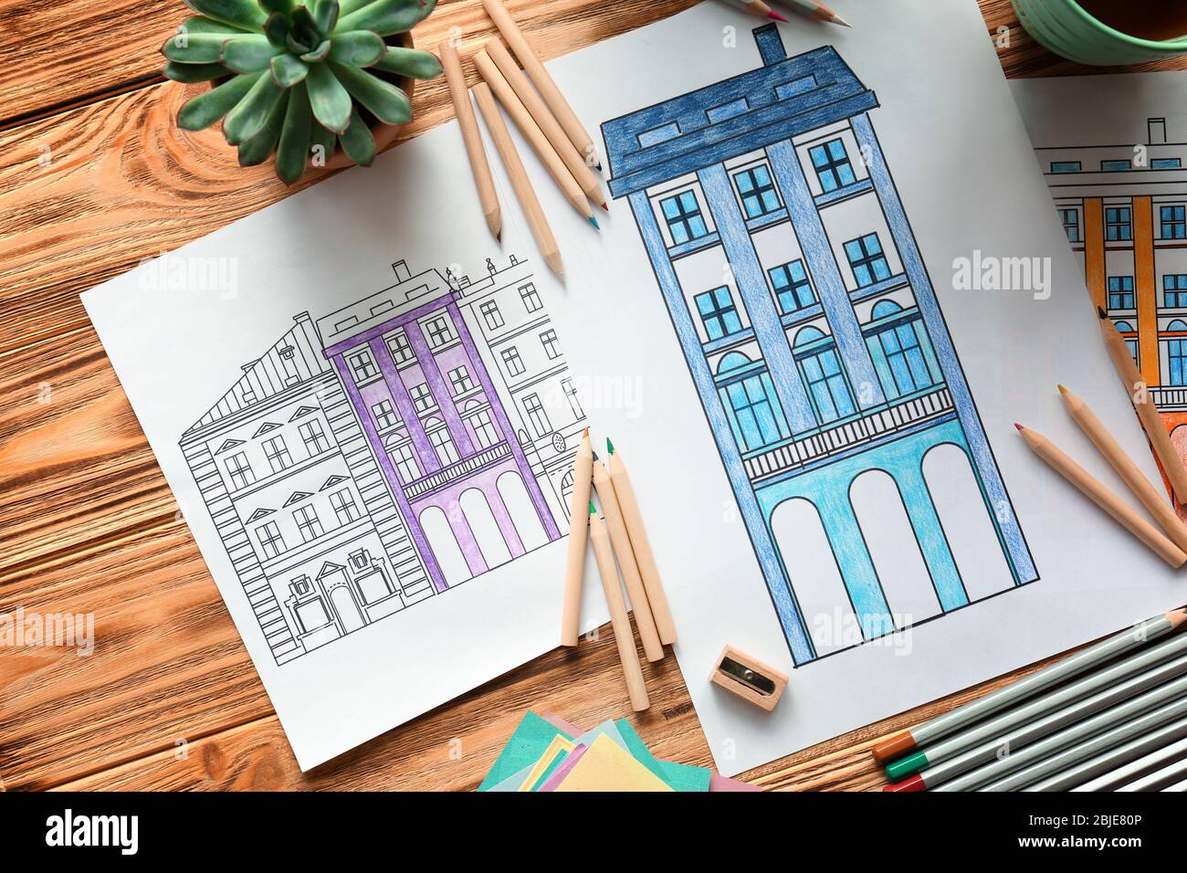 Composition of colouring pictures and pencils on wooden table Stock ...