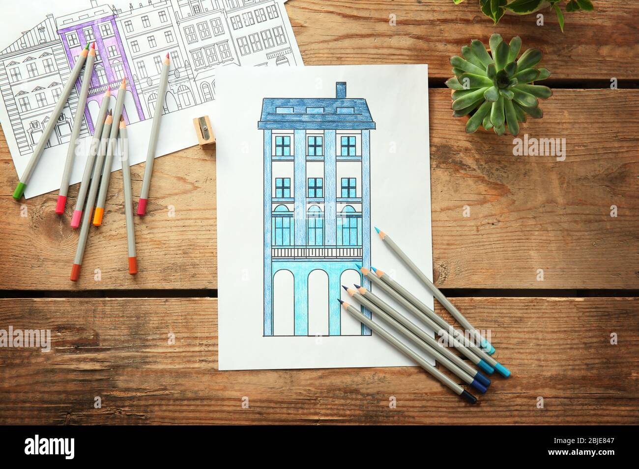 Composition of colouring pictures and pencils on wooden table Stock ...