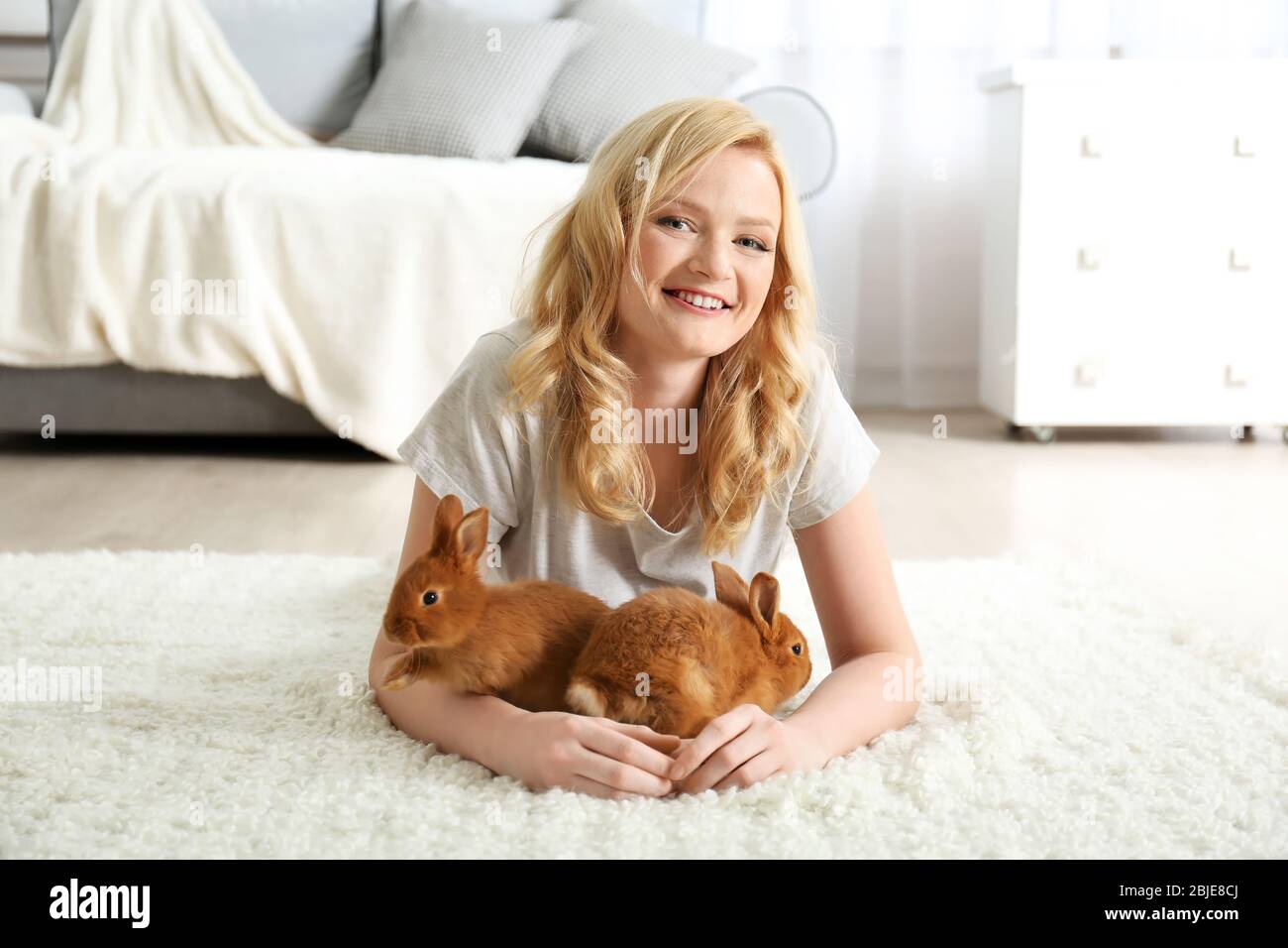 Beautiful girl with small rabbits at home Stock Photo - Alamy