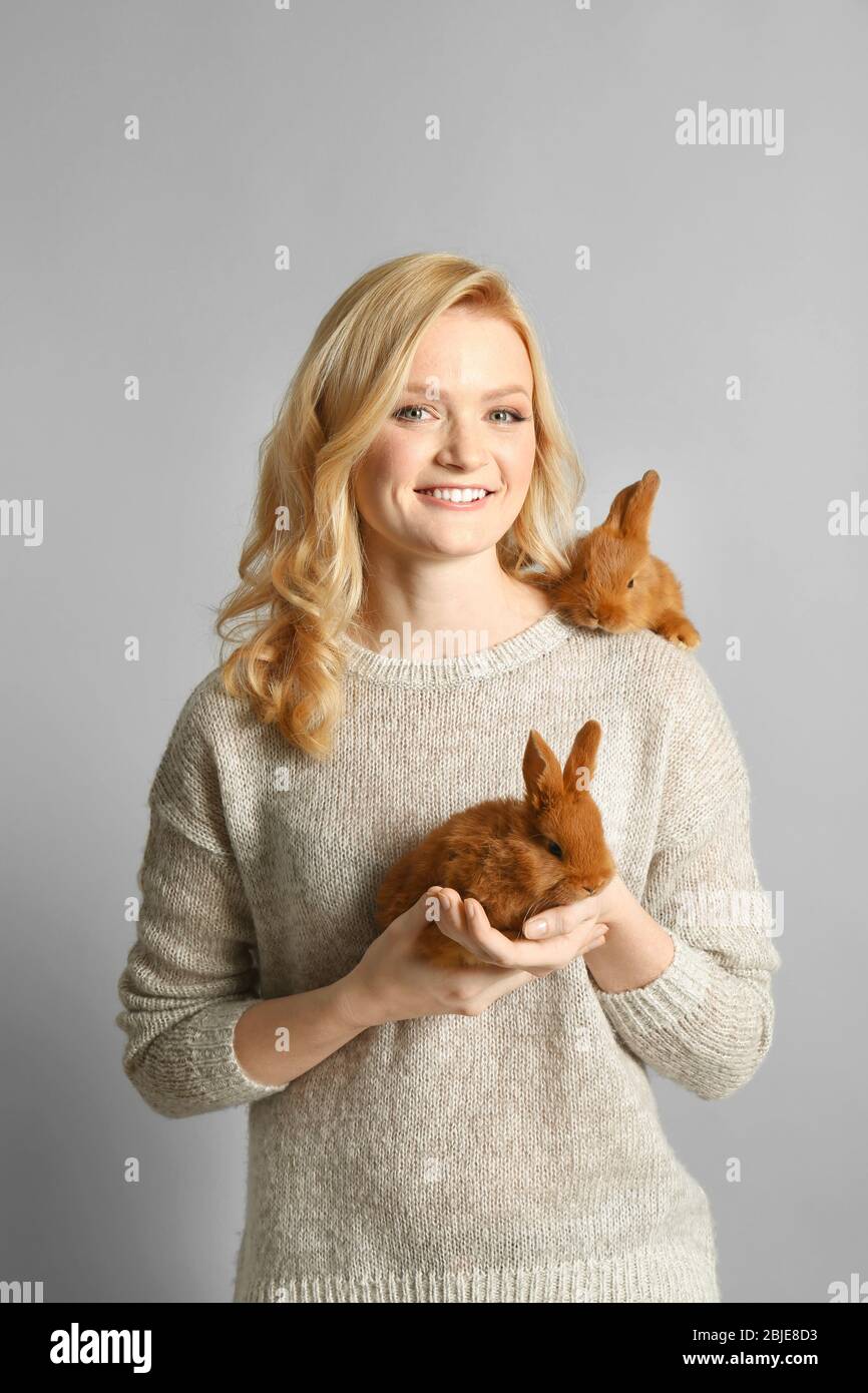 Beautiful girl with small rabbits on grey background Stock Photo - Alamy