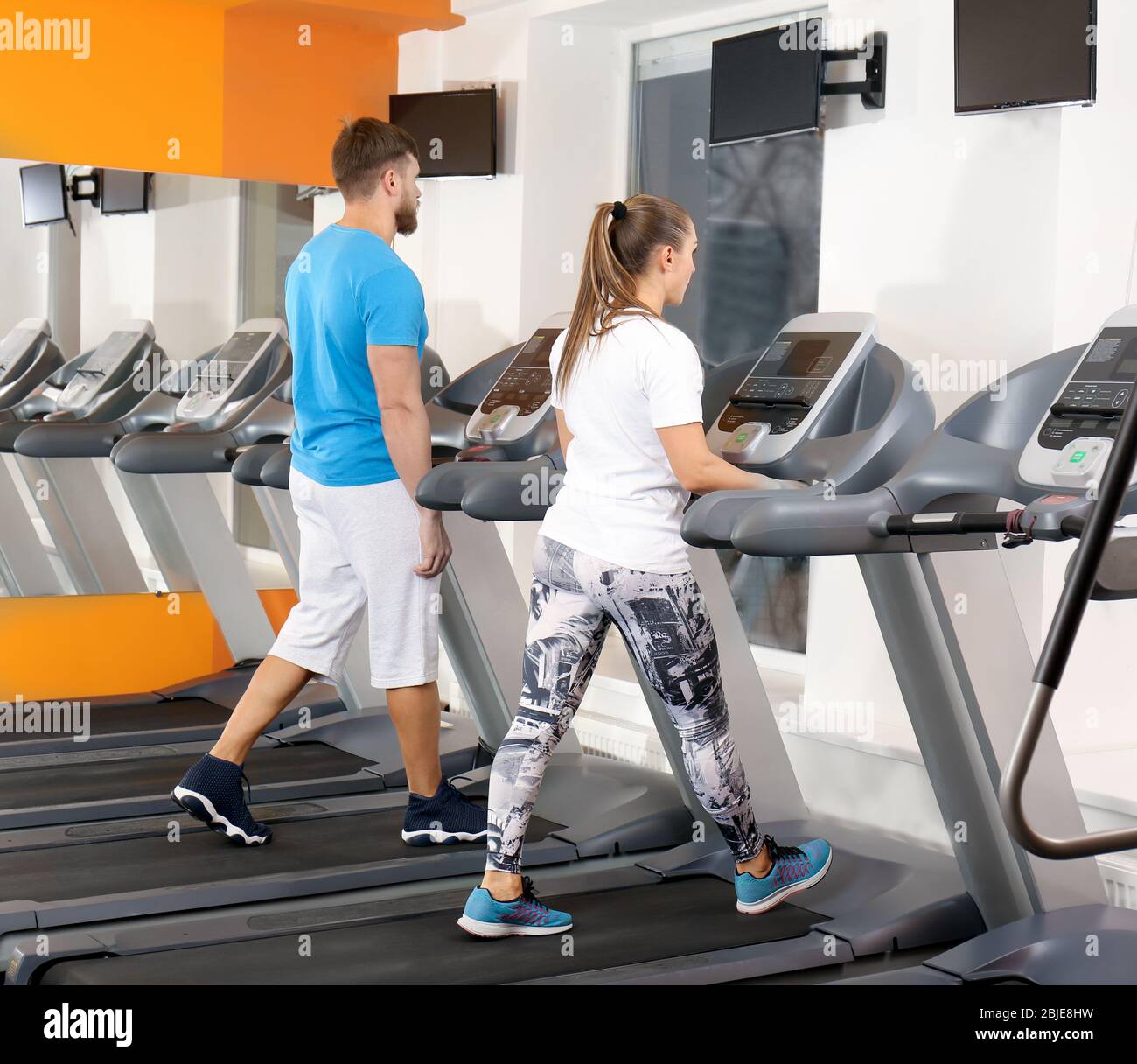Young people running on treadmills in gym Stock Photo - Alamy