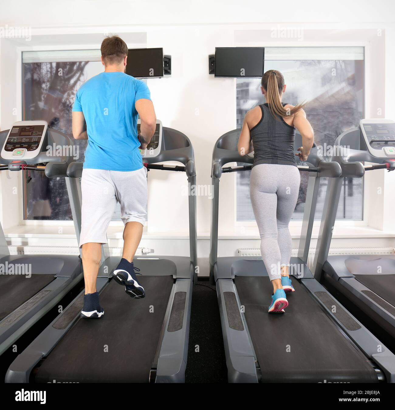 Young people running on treadmills in gym Stock Photo - Alamy