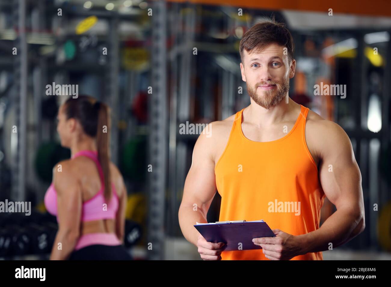 Personal trainer holding clipboard with training plan in gym Stock ...