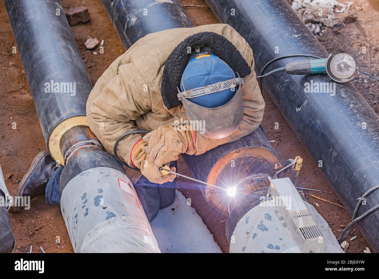 Welder worker welds new metal pipe Stock Photo - Alamy