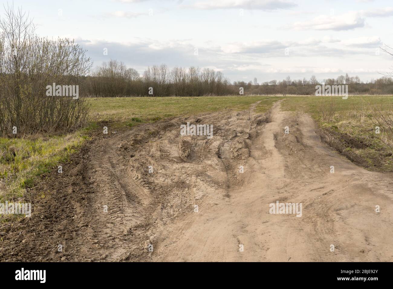 dirt damaged rural spring road in a field. concept of problem with the ...