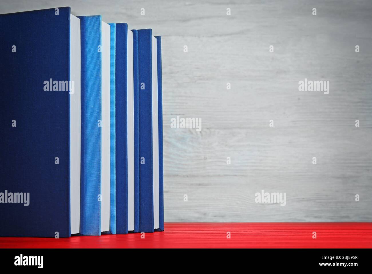 Books in a row on red wooden table Stock Photo - Alamy