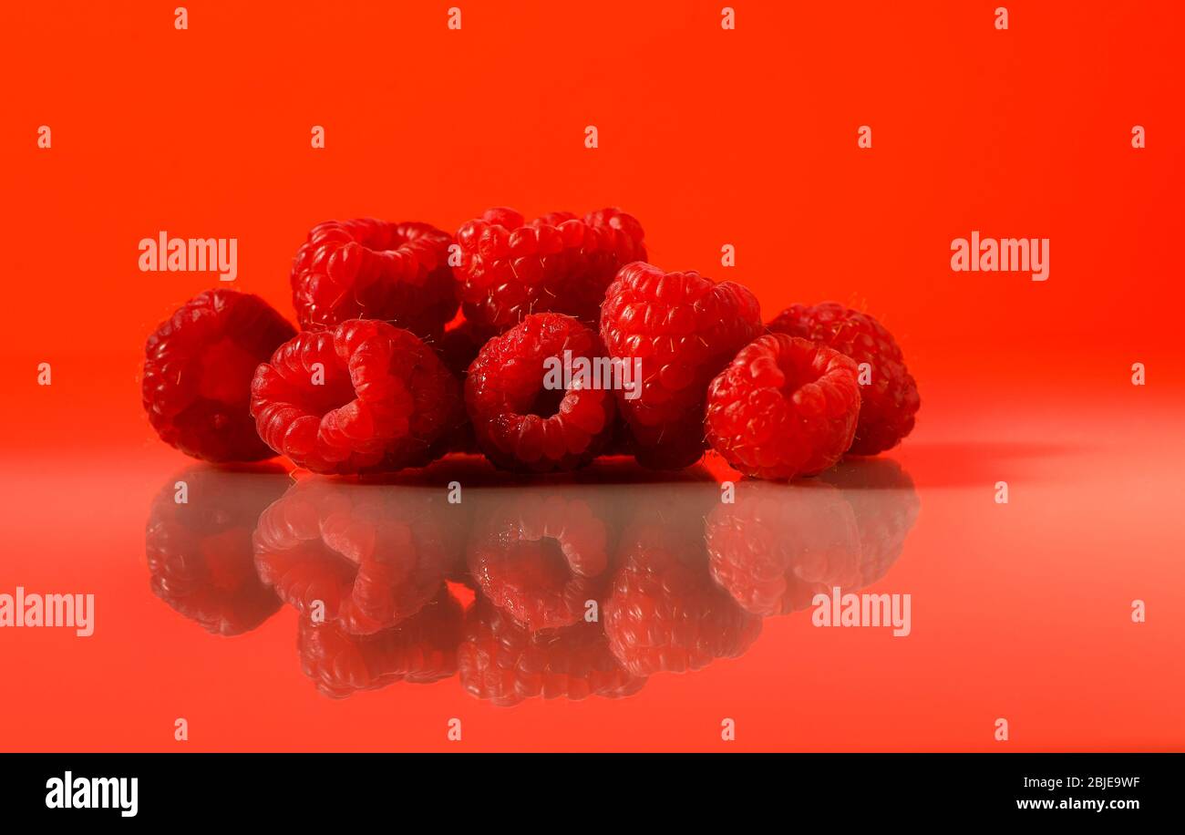 A pile of raspberry's on a red background with a reflection Stock Photo ...