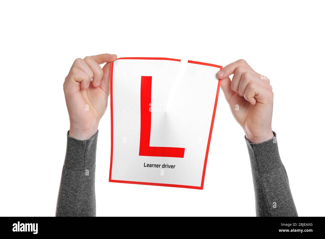 Hands of young man tearing learner driver sign on white background ...