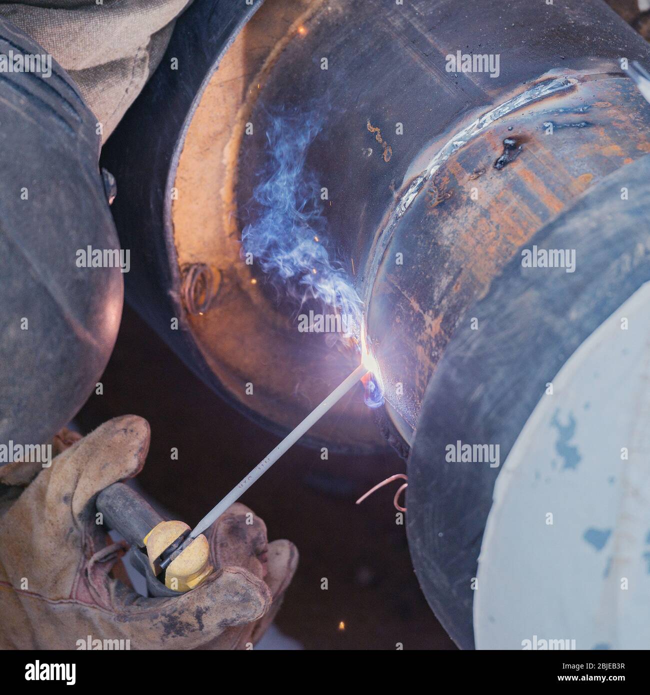 Welder worker welds new metal pipe Stock Photo - Alamy
