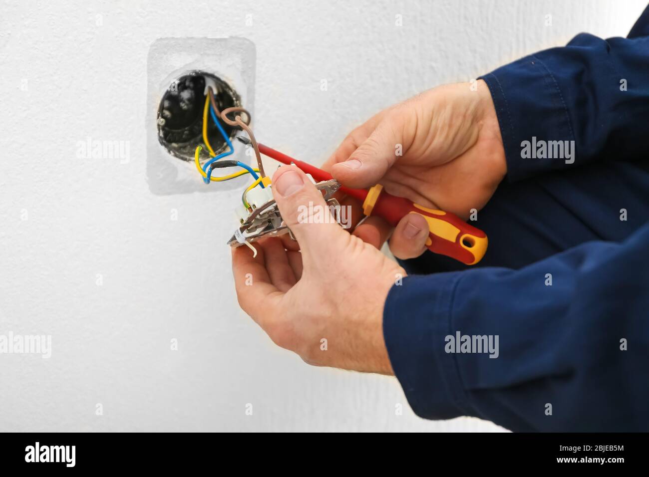 Electrician disassembling wall socket in new building, closeup Stock ...