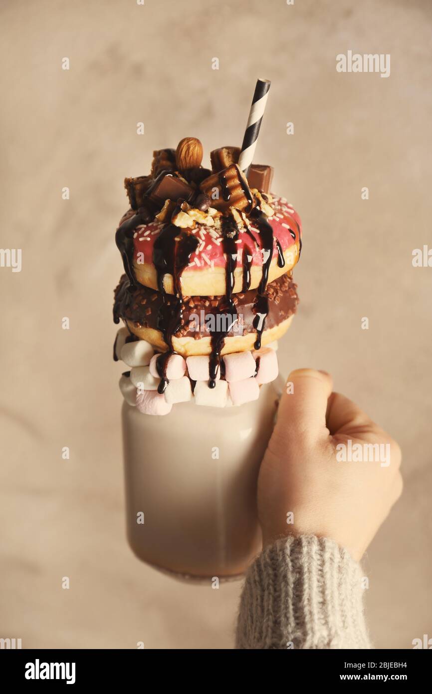 Hand holding milkshake, donuts and other sweets in jar on color ...
